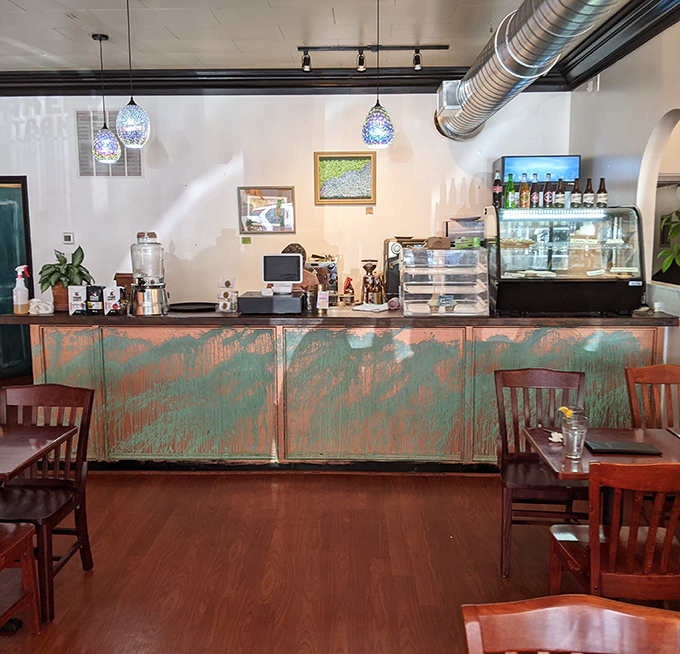 The counter's weathered turquoise patina tells stories of countless coffees poured and conversations shared beneath those twinkling pendant lights.