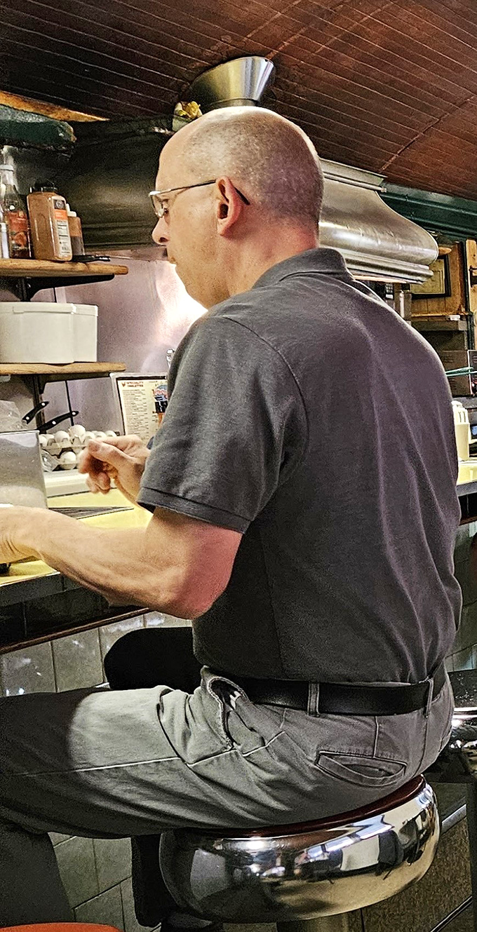 The cook works his morning magic at the grill, a breakfast conductor orchestrating a symphony of sizzles and aromas.