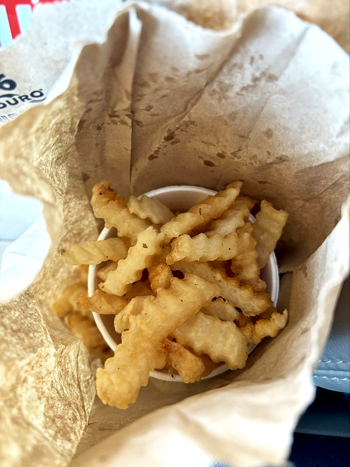 Crinkle-cut fries nestled in their paper bag&mdash;simple, golden, perfectly salted companions that know their supporting role and play it brilliantly.