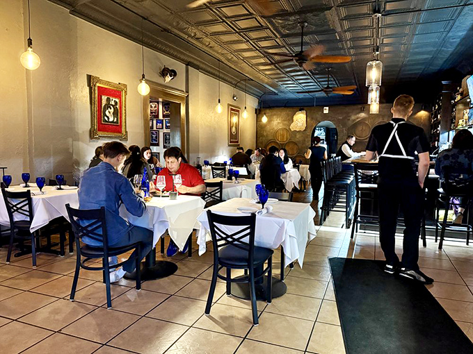 White tablecloths and cobalt blue glasses create a canvas for culinary artistry, while the ornate ceiling reminds you that sometimes, looking up reveals unexpected beauty.