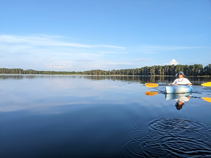 Paddling into perfect stillness. The morning glass on Lake Louisa turns kayaking into a meditation session with occasional fish sightings.