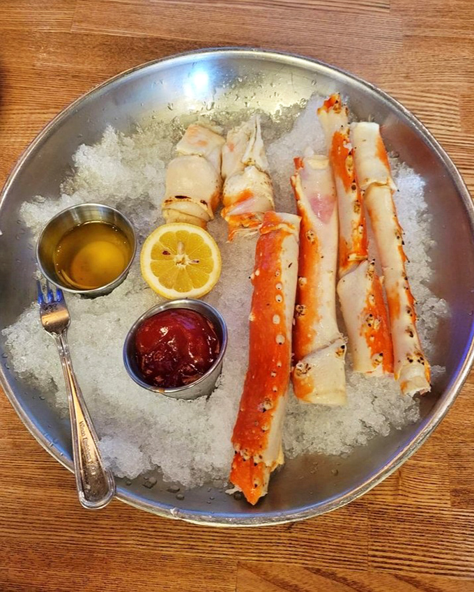 King crab legs presented like oceanic royalty on a throne of ice, accompanied by the only two condiments worthy of their majesty&mdash;drawn butter and cocktail sauce.