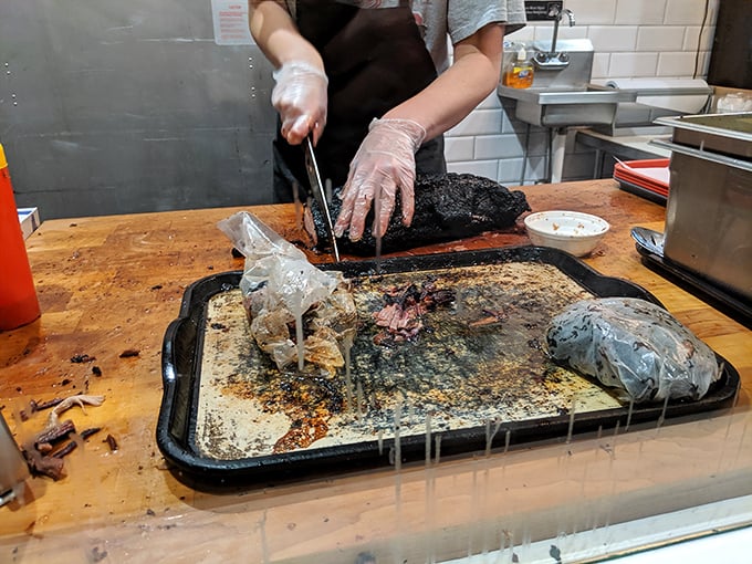 Behind every great barbecue is a skilled hand wielding a knife. This kitchen action shot reveals the craftsmanship that goes into each perfectly sliced portion.