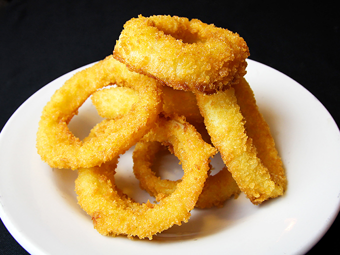 Golden-fried onion rings stacked like delicious halos&mdash;crispy on the outside, tender within, and impossible to stop eating once you've started.