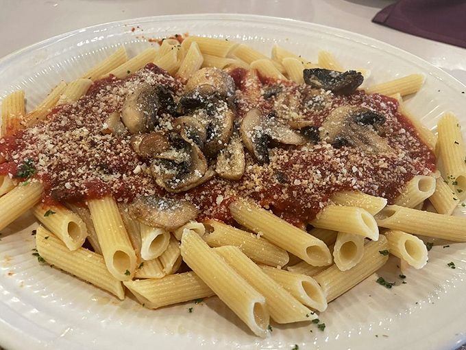 Penne pasta swimming in red sauce with sautéed mushrooms—simple ingredients transformed into something that makes you want to applaud.