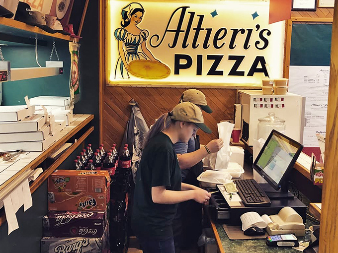 Behind the counter, where pizza dreams come true and vintage signage tells the story of decades of delicious dedication.