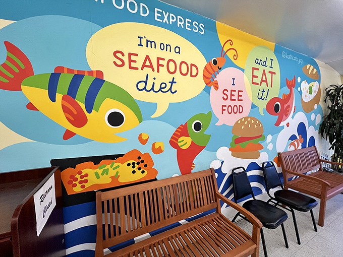 The whimsical wall mural declares "I'm on a SEAFOOD diet &ndash; I SEE FOOD and I EAT it!" &ndash; dad joke humor that somehow works perfectly in this unpretentious space.