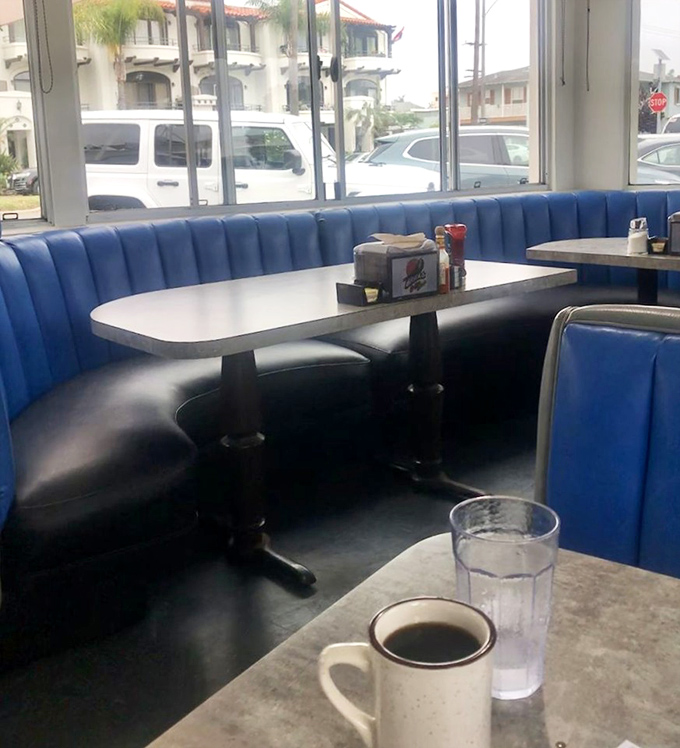 Classic blue vinyl booths provide comfortable seating where conversations flow as smoothly as the coffee refills.