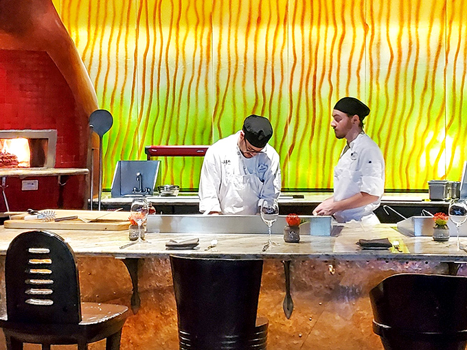 Chefs at work behind that stunning backdrop, turning dinner service into dinner theater magic.