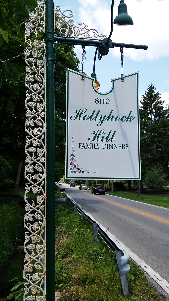 The elegant Hollyhock Hill sign stands sentinel along the roadway, a beacon guiding hungry travelers to fried chicken paradise.