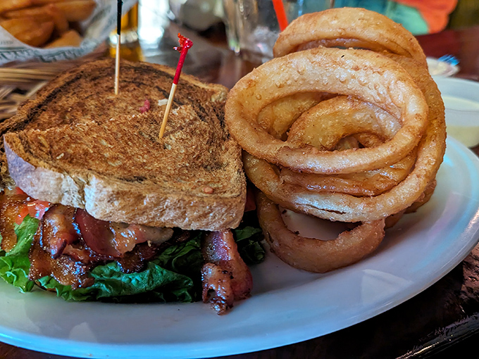 This sandwich isn't just lunch – it's an engineering marvel of bacon, lettuce and tomato, flanked by onion rings that could double as halos.