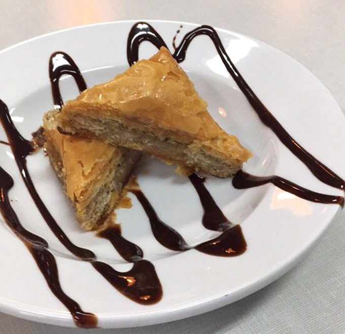 Baklava gets a chocolate makeover! Flaky phyllo, honey-soaked nuts, and artistic chocolate drizzle elevate this Greek classic to new heights.