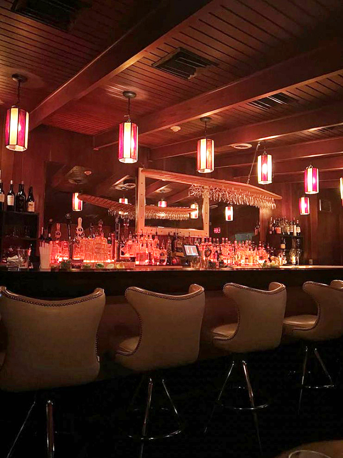 The bar glows with amber promise—a temple to properly made cocktails where bartenders treat ice as seriously as the spirits they pour.