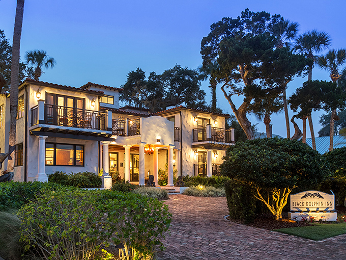 The Black Dolphin Inn glows at twilight, Mediterranean elegance meets Florida charm. Brick pathways lead to this boutique accommodation that feels worlds away from ordinary.