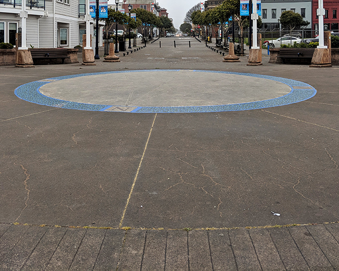 The boardwalk's circular mosaic creates a meditative focal point with the historic commercial district stretching beyond, inviting exploration on foot.