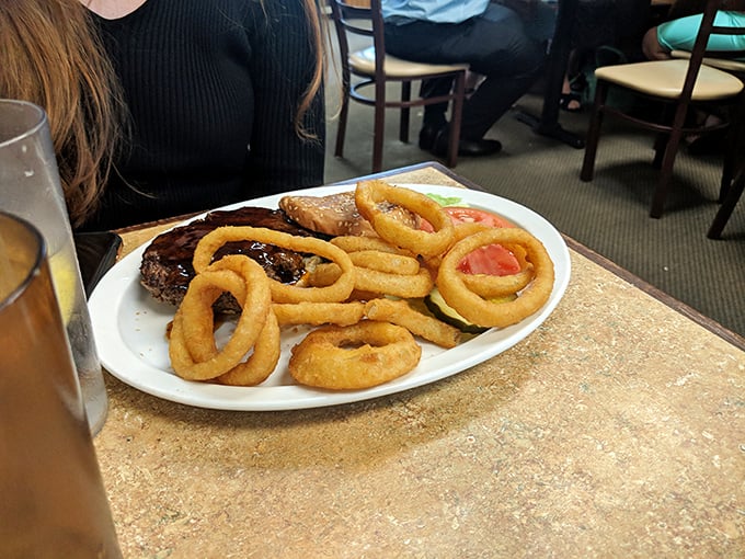 A burger flanked by golden onion rings standing at attention like delicious sentinels guarding the main attraction.