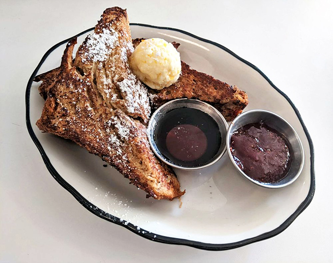 Challah French toast that makes pancakes jealous. That scoop of butter melting into powdered sugar is performing a delicious disappearing act.