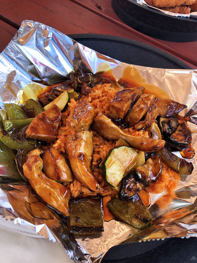 Chicken and veggies nestled on a bed of rice, all wrapped in foil like the culinary present you didn't know you needed.