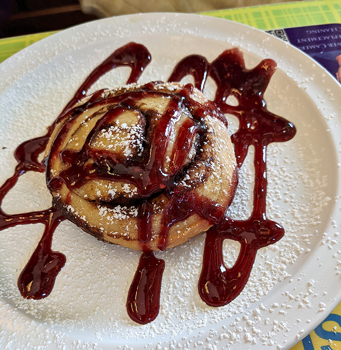 A cinnamon roll wearing chocolate drizzle like it's headed to the breakfast prom &ndash; and winning king.