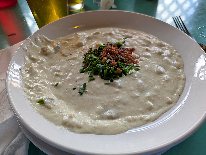 Clam chowder thick enough to float a spoon, garnished with herbs and what looks like bacon because, why not?
