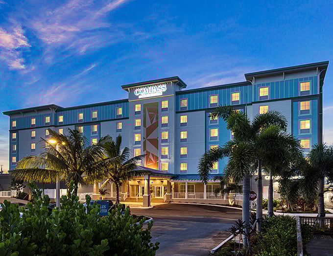 The Compass Hotel glows at twilight, beckoning travelers with the promise of vacation vibes without emptying the retirement fund.