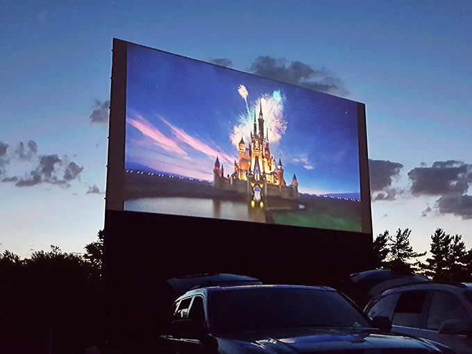Daylight fades as families gather, cars positioned just-so for the perfect view of tonight's cinematic adventure.