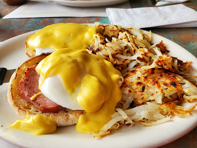 Eggs Benedict with a cascade of hollandaise that would make a French chef nod in approval. Crispy hash browns standing guard on the side.