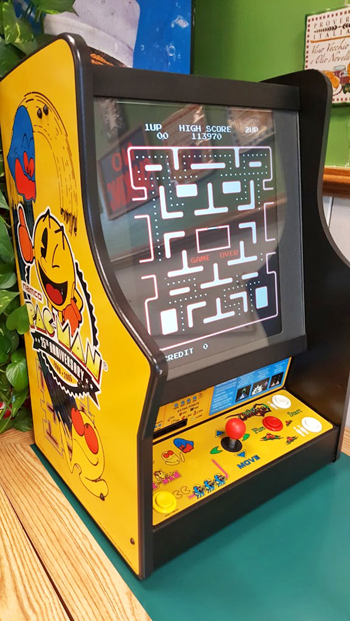 A vintage Pac-Man cabinet in the corner &ndash; because nothing complements a slice like the sweet symphony of 8-bit nostalgia.