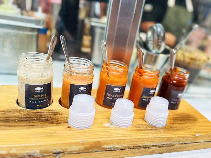 A wooden board showcases Holbox's arsenal of house-made hot sauces, each jar a different shade of delicious danger.