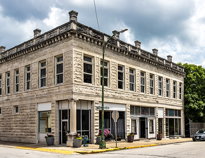 This limestone corner building anchors its intersection with quiet dignity, its classical details a reminder that even small towns once built for permanence.