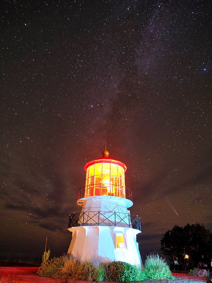 Under a canopy of stars, the lighthouse glows like a cosmic beacon. No filter needed for this magical nighttime transformation.
