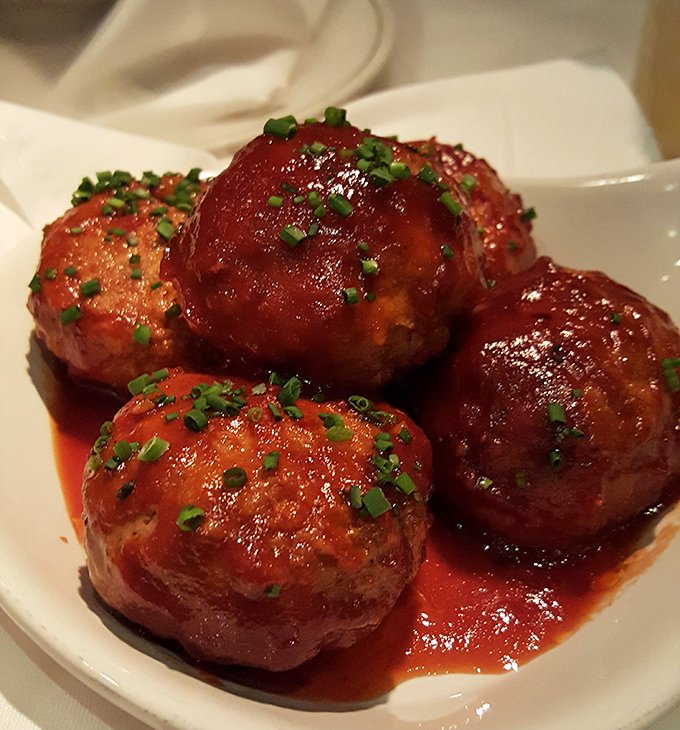 These meatballs aren't just appetizers; they're flavor bombs dressed in their Sunday best, topped with chives that add both color and sass.
