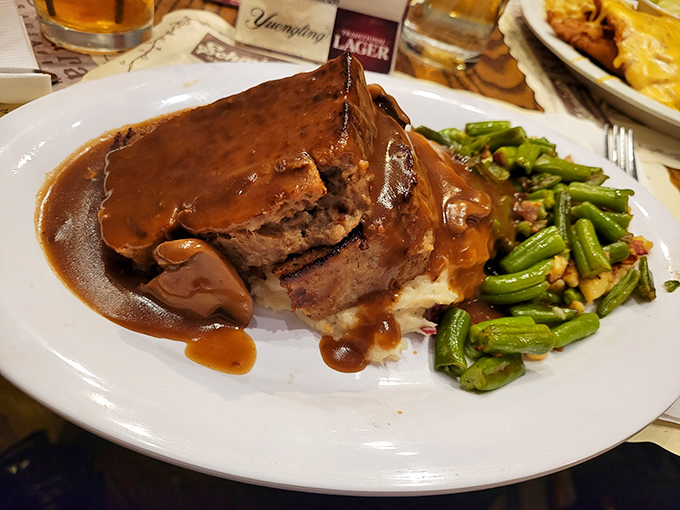 This isn't just meatloaf—it's a monument to comfort food, swimming in gravy rich enough to make your cardiologist wince and your soul sing.