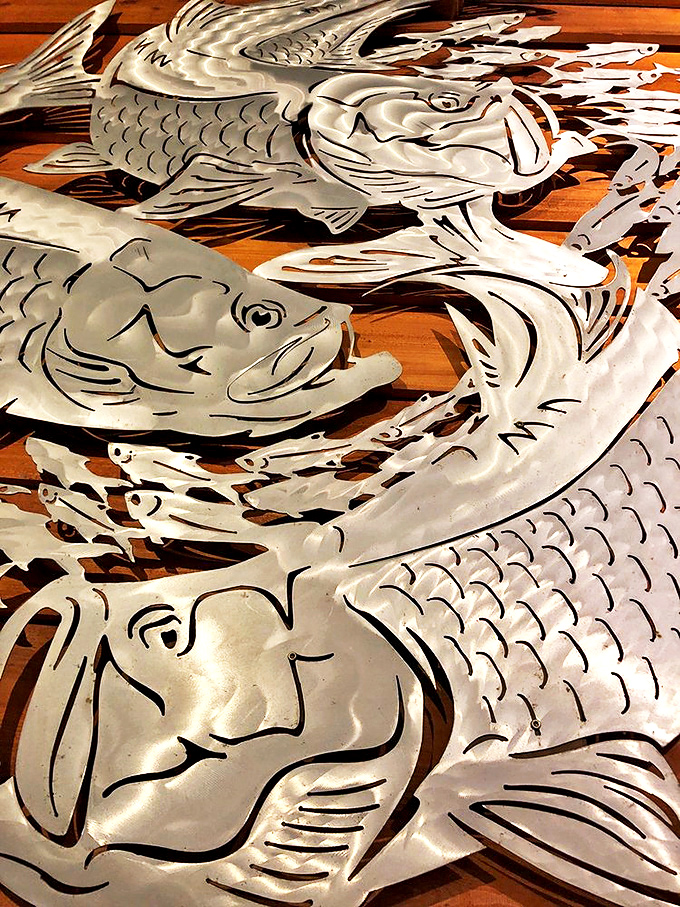 Metal fish sculptures dance across wooden walls – a shimmering school of silver art that captures the restaurant's devotion to all things aquatic.