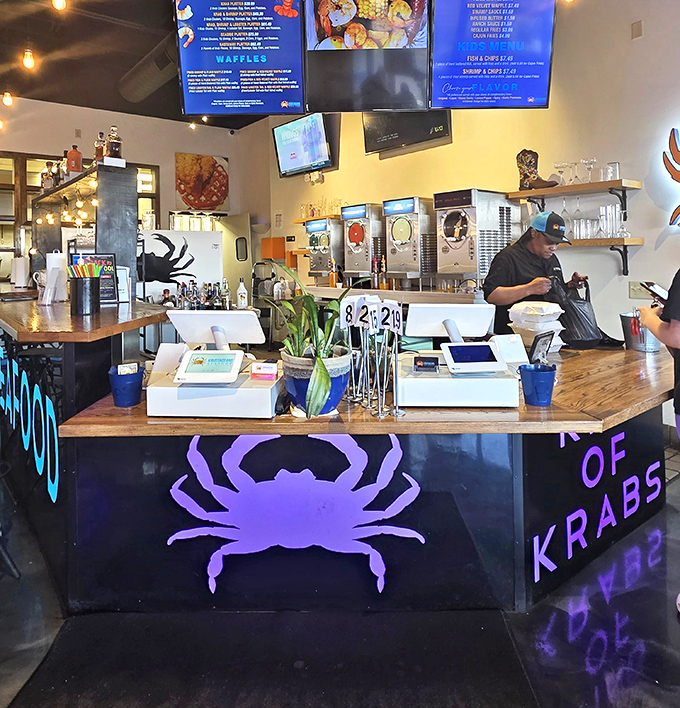 Behind this counter, seafood dreams come true. The neon purple crab silhouette serves as a beacon for the butter-soaked treasures ahead.