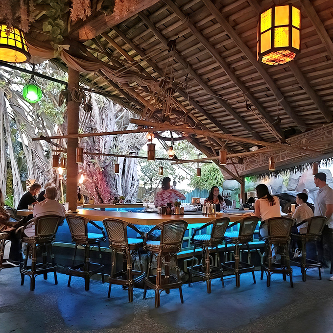 This outdoor bar blends seamlessly with nature, offering tropical drinks under a thatched roof while palm fronds dance overhead.