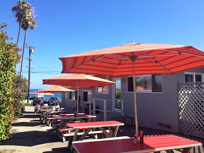 Orange umbrellas provide shade for the sun-kissed feasts below. Al fresco dining with a side of Pacific Ocean panorama.