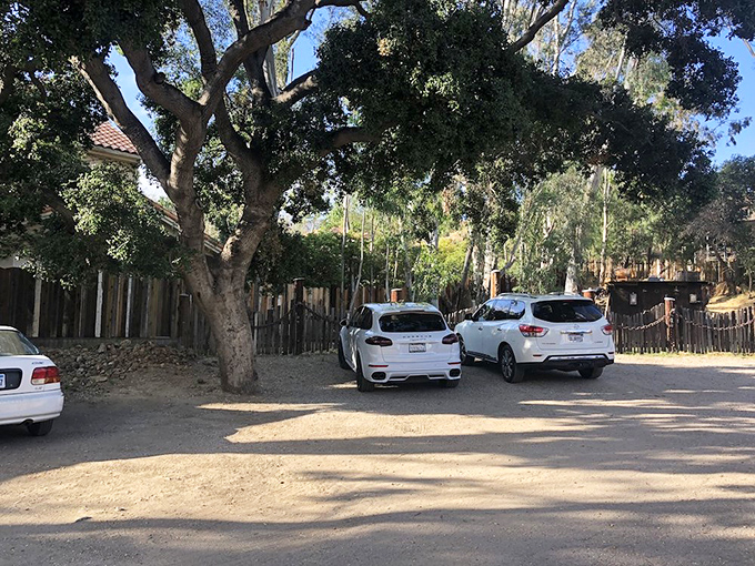 The parking area under ancient oaks &ndash; where luxury SUVs now rest where horses once stood, the California mountains standing sentinel in the background.