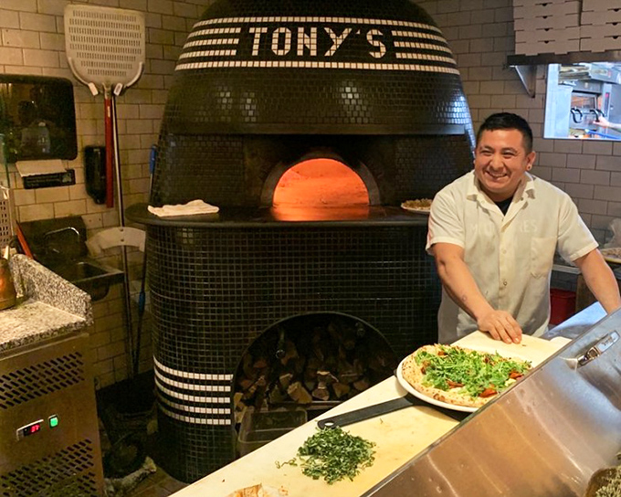 The maestro at work! That wood-fired oven isn't just cooking equipment&mdash;it's a time machine transporting you straight to Naples.