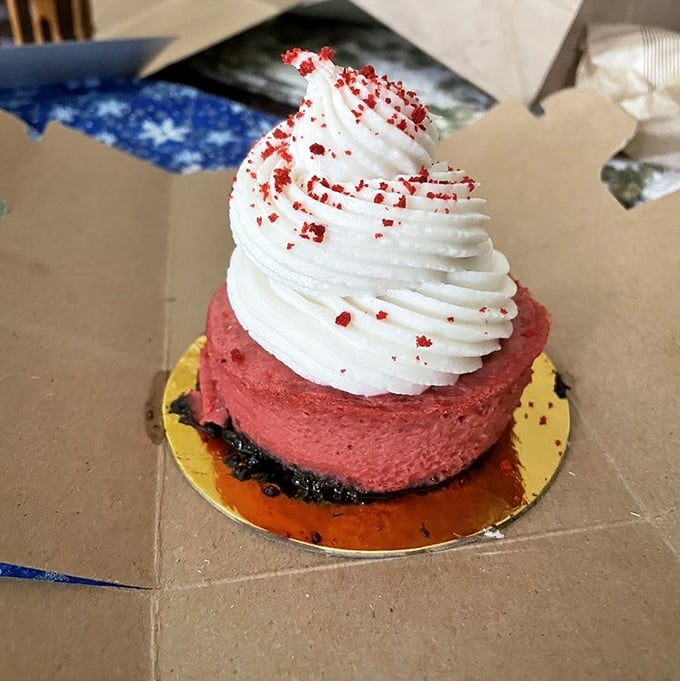 Red velvet cheesecake crowned with a cloud of whipped topping. The contrast between crimson cake and snowy frosting is visually stunning.