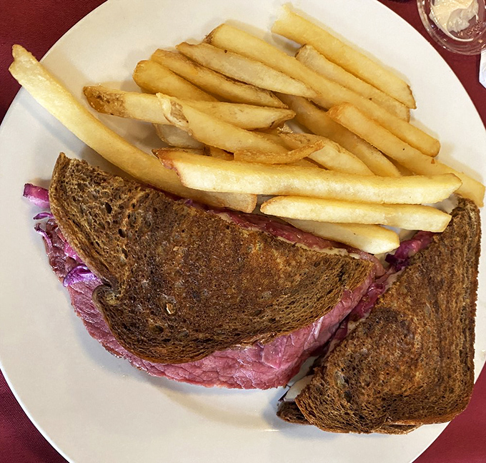 The Reuben—where corned beef, sauerkraut, and Swiss cheese meet in a grilled rye summit that resolves all international tensions. Those fries aren't just sidekicks; they're co-stars.