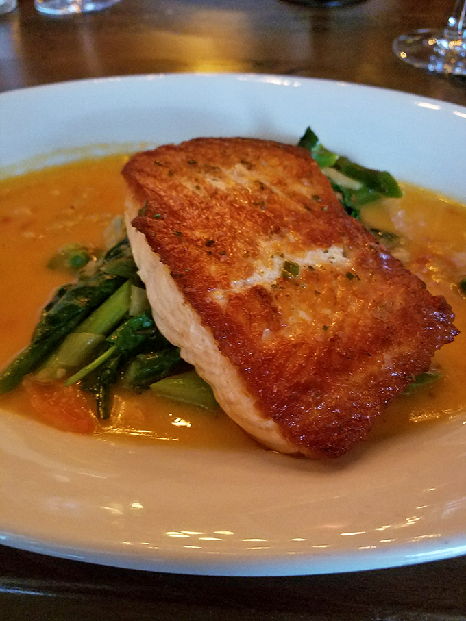 This isn't just fish&mdash;it's seafood architecture, perfectly balanced on a bed of greens with a sauce that deserves its own fan club.