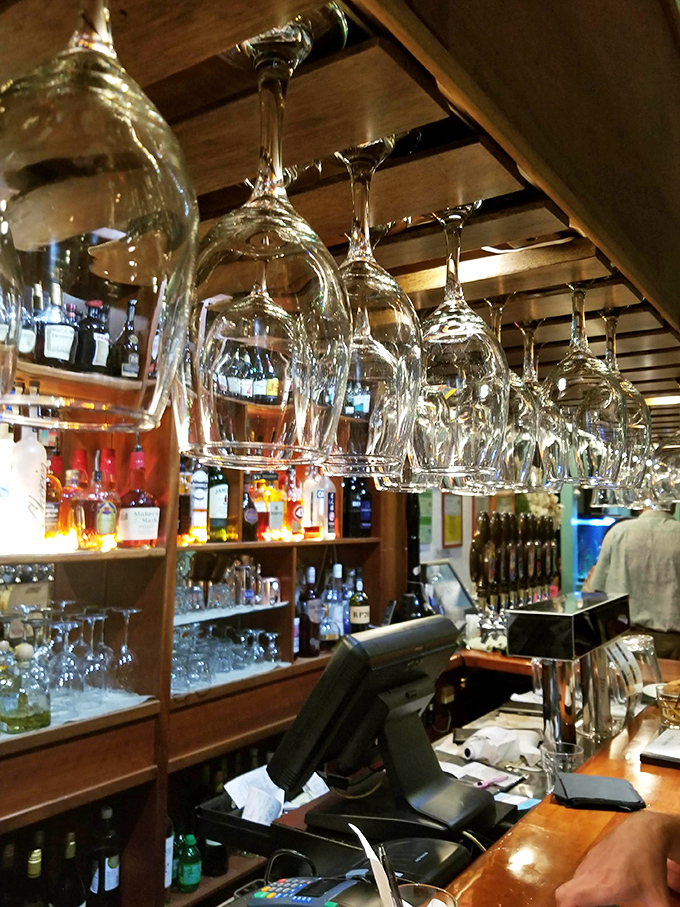 Wine glasses hang like crystal stalactites above the bar, waiting to enhance your dining experience with perfect coastal pairings.