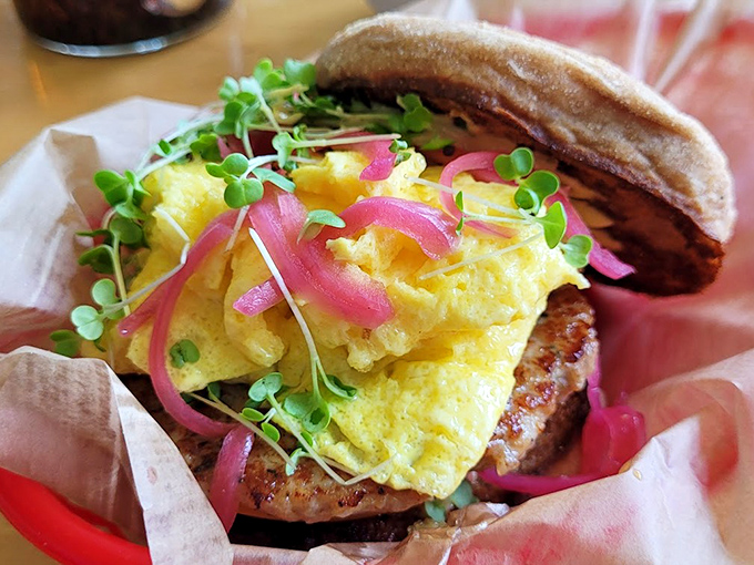 The breakfast sandwich in its natural habitat&mdash;nestled in paper, bursting with golden eggs and those magical pink pickled onions that brighten everything they touch.