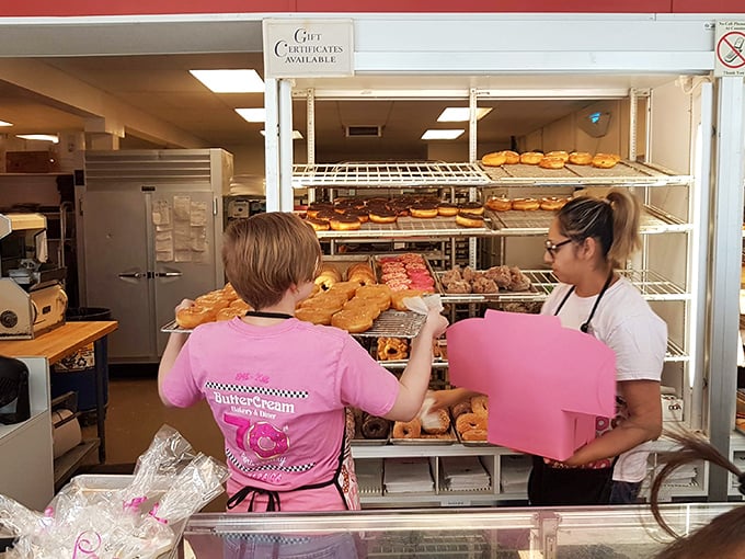 Pink-shirted staff carefully arranging donuts&mdash;the unsung heroes ensuring your morning starts with perfectly arranged circles of joy.