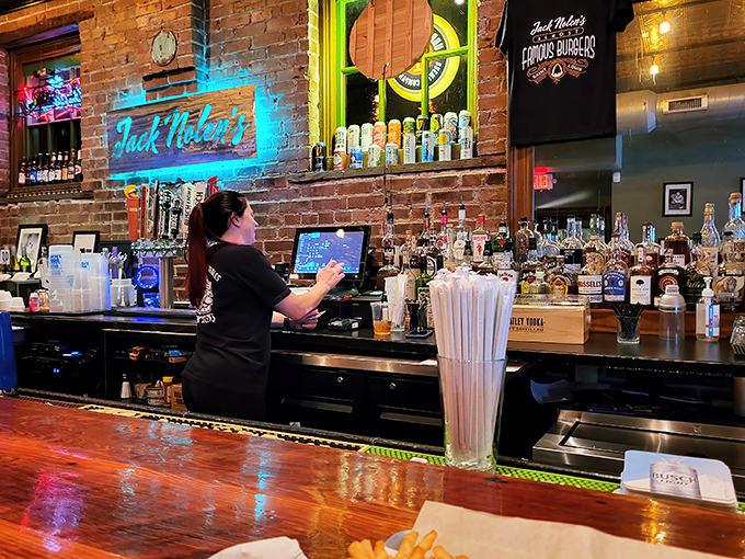 The neon glow of the Jack Nolen's sign bathes the brick wall in blue light while the bartender crafts the next round of happiness.