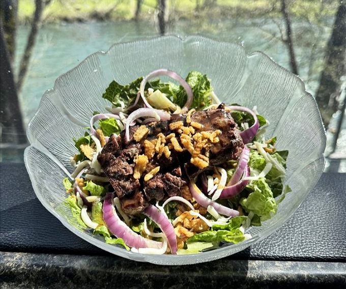 A salad with a view! Fresh greens topped with perfectly seared steak beside the Rogue River—proving healthy choices can still be indulgent.