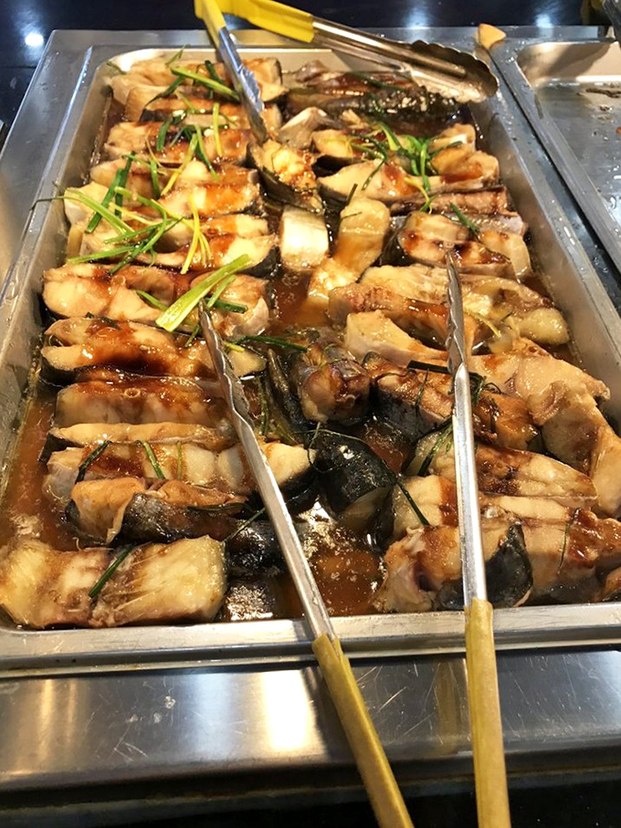 Steamed fish bathing in savory sauce, garnished with green onions. Simple preparation that lets the quality of the fish shine through.