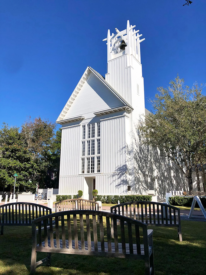 The Chapel at Seaside stands crisp and white against the Florida blue sky, its distinctive tower reaching skyward like a beacon of architectural simplicity and grace.