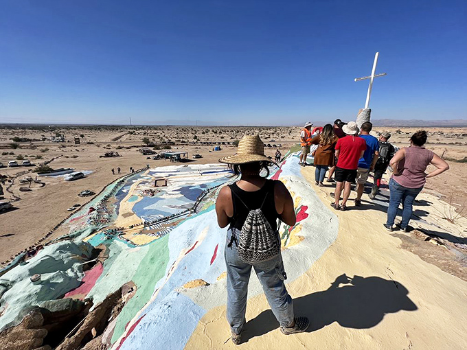 Visitors stand at the summit, taking in panoramic views of Slab City and the surrounding desert that make the climb worthwhile even on scorching days.